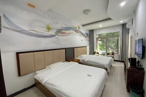 Quarto de hotel com duas camas, um mural na parede, uma televisão e uma janela com vista para áreas verdes.