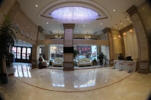 Um hall espaçoso com um grande candelabro, áreas de estar e um balcão de recepção.