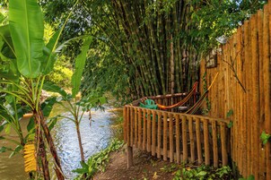 Cerca de madeira, bambu e um corpo de água.