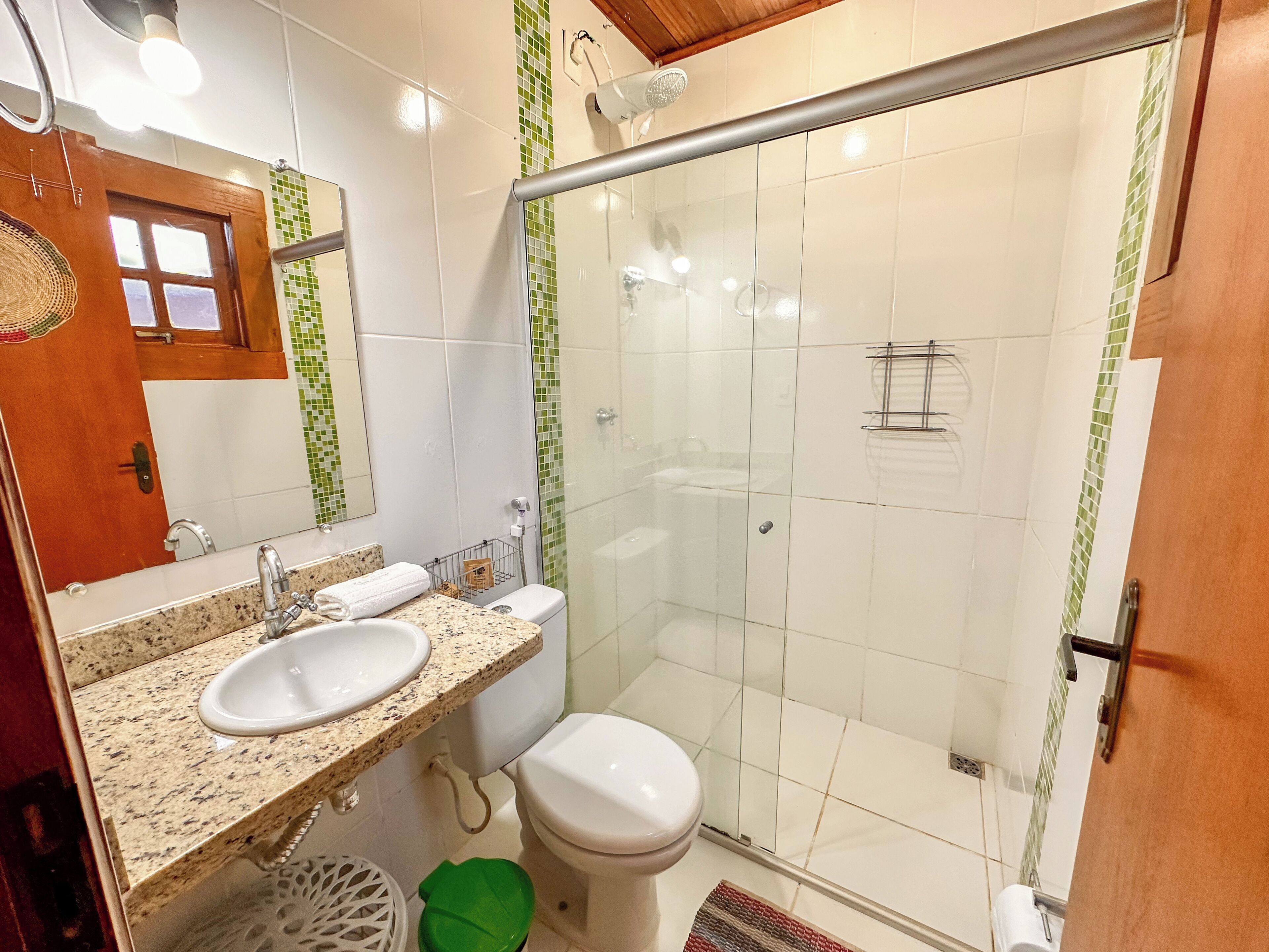 Casa de banho com duas pias, sanita e cabine de duche em vidro.