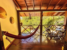 Uma rede em um quarto de madeira com vista para o verde lá fora.
