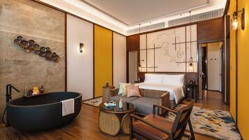 Quarto de hotel moderno com uma banheira grande, cama com cabeceira de madeira, um mapa na parede e uma pequena mesa redonda com um vaso.