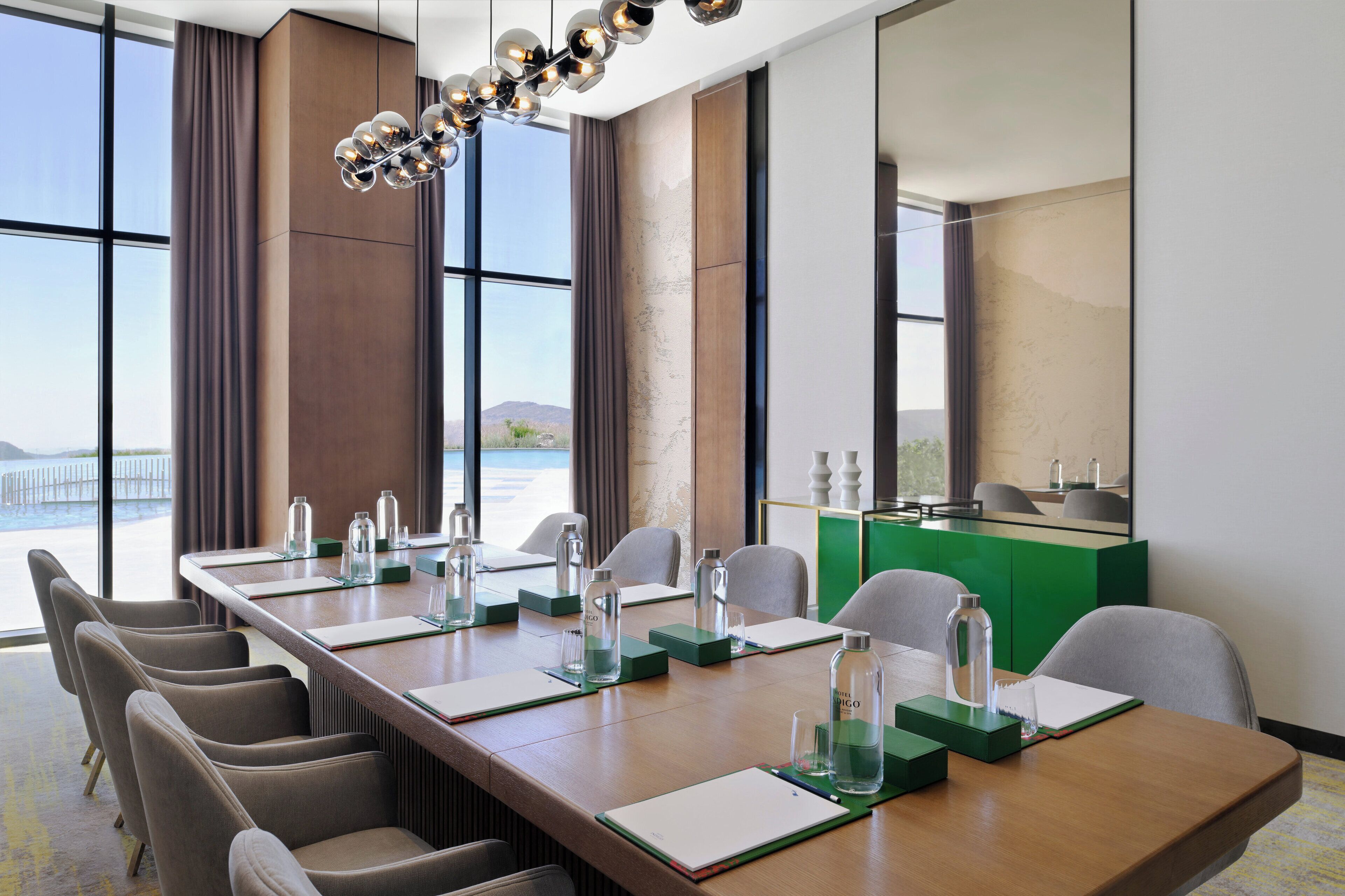 Sala de conferências com uma mesa comprida, cadeiras e vista para o exterior.