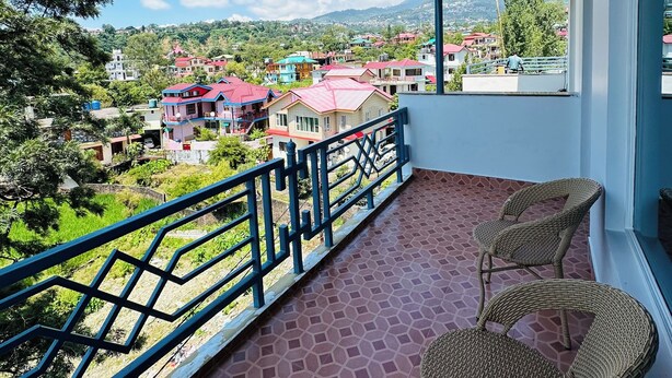 Uma varanda com cadeiras de vime, piso de azulejos e vista para casas e vegetação.