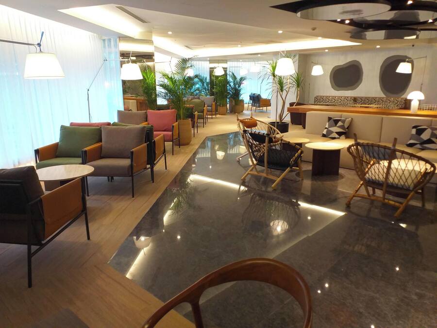 Um lobby de hotel moderno com diversas opções de assento, incluindo sofás, cadeiras e um bar.