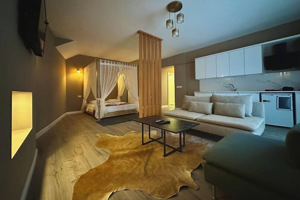 Uma sala de estar moderna com uma cama, um sofá, uma mesa de centro e um espaço de cozinha.