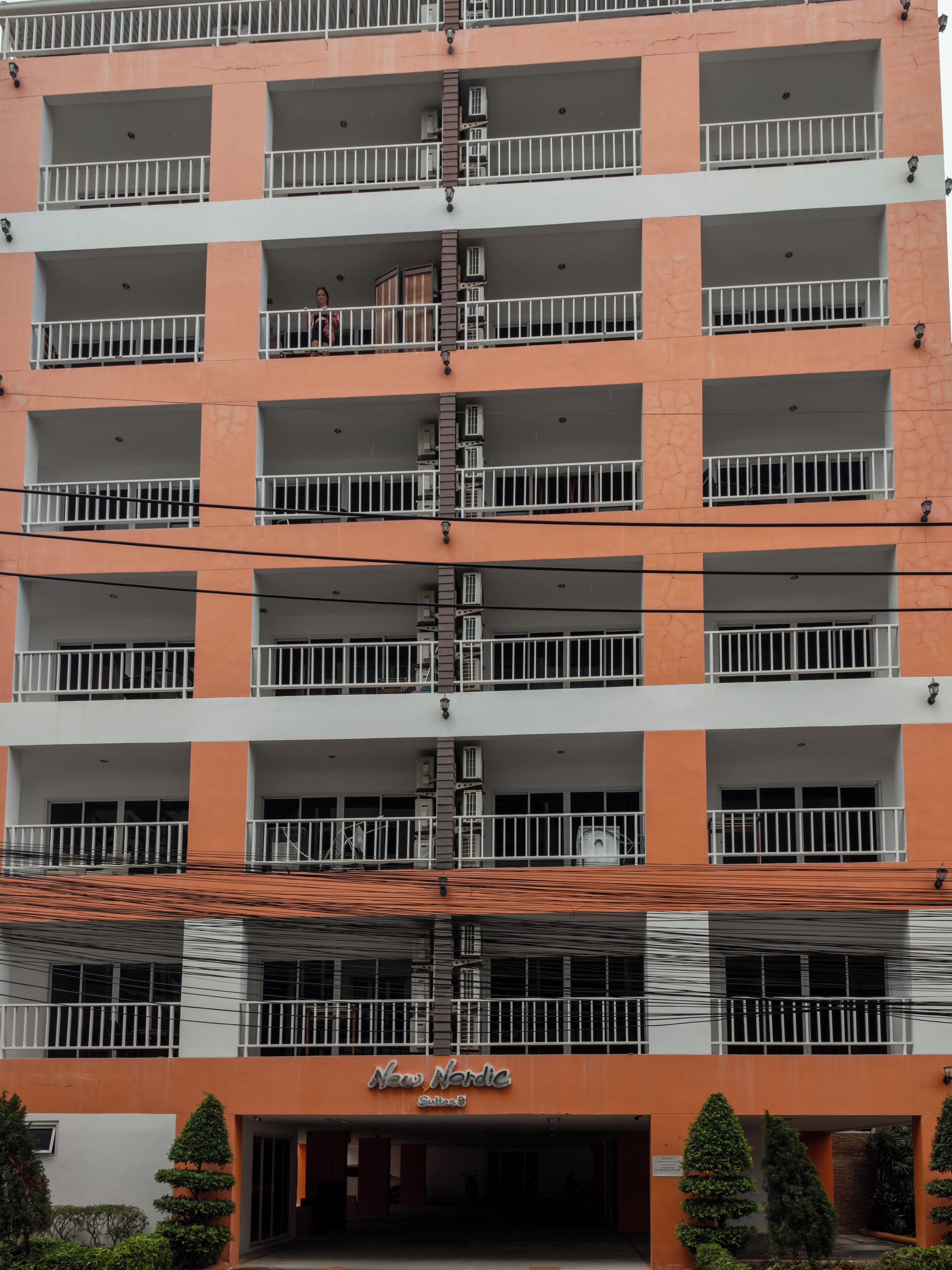 Um edifício com vários andares, varandas, um átrio central e uma placa com a inscrição 'New Nordic Suites'.