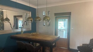 Uma sala de jantar com mesa de madeira, cadeiras e luminárias pendentes.