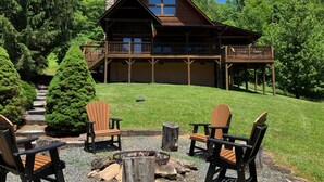 Uma cabana com varanda e área de fogueira com cadeiras Adirondack.