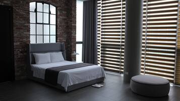 Um quarto moderno com uma cama grande, parede de tijolos e uma janela ampla com persianas.
