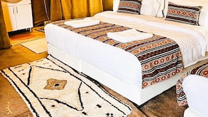 Um quarto aconchegante com uma cama grande, uma mesinha de cabeceira e um espelho.