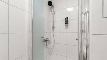 Chuveiro com chuveiro manual, massageador manual e uma garrafa de shampoo na parede.