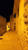 Um beco estreito com edifícios de pedra, uma porta visível e uma janela.