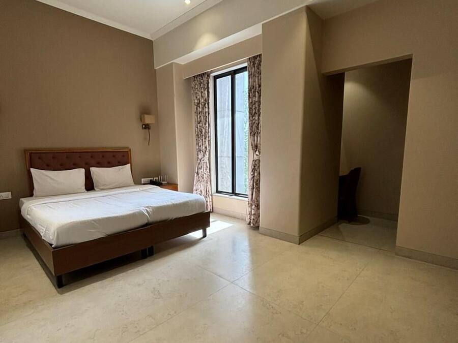 Um quarto espaçoso com uma cama grande, uma janela com cortinas e um guarda-roupa embutido.