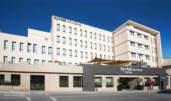 Um edifício moderno de hotel com uma placa de destaque que diz "Kyriad Prestige Hotel".
