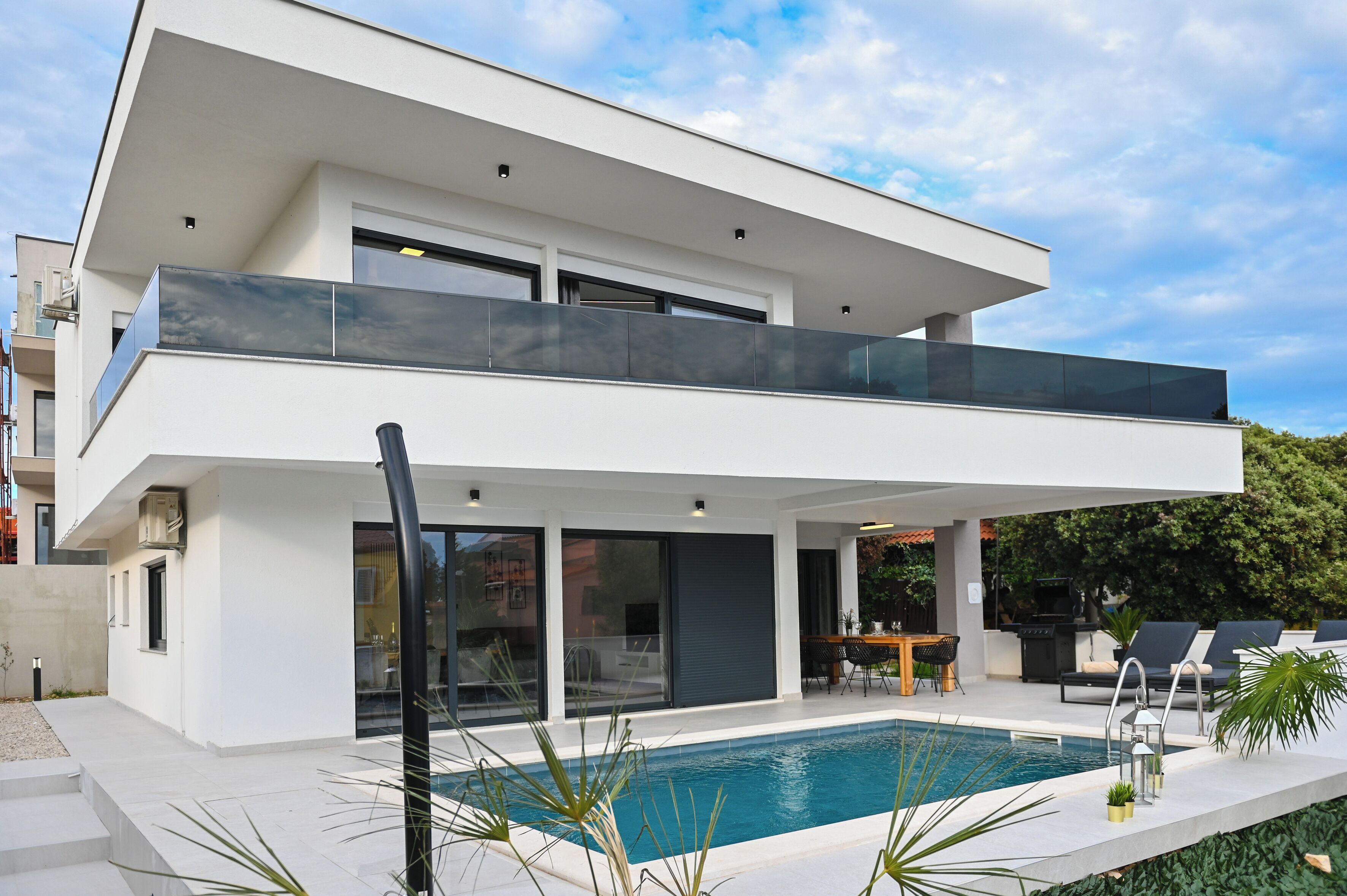 Uma casa moderna de dois andares com piscina, janelas amplas e varanda.