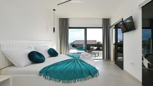 Quarto de hotel moderno com uma cama grande, uma televisão na parede e vista para o exterior.