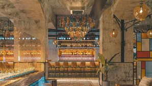 Uma área de bar com um balcão comprido, vários banquetas e uma variedade de garrafas nas prateleiras.