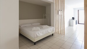 Quarto moderno com cama, divisória de madeira e uma pequena mesa com chaleira.