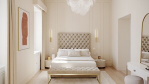 Quarto com cabeceira estofada, uma cama grande, mesas de cabeceira, um banquinho, um espelho e um candelabro.