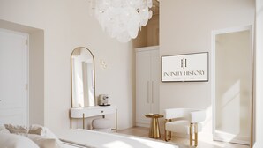 Quarto moderno e minimalista com uma cama grande, uma toucador com espelho, um espelho com moldura dourada e uma placa emoldurada com a inscrição 