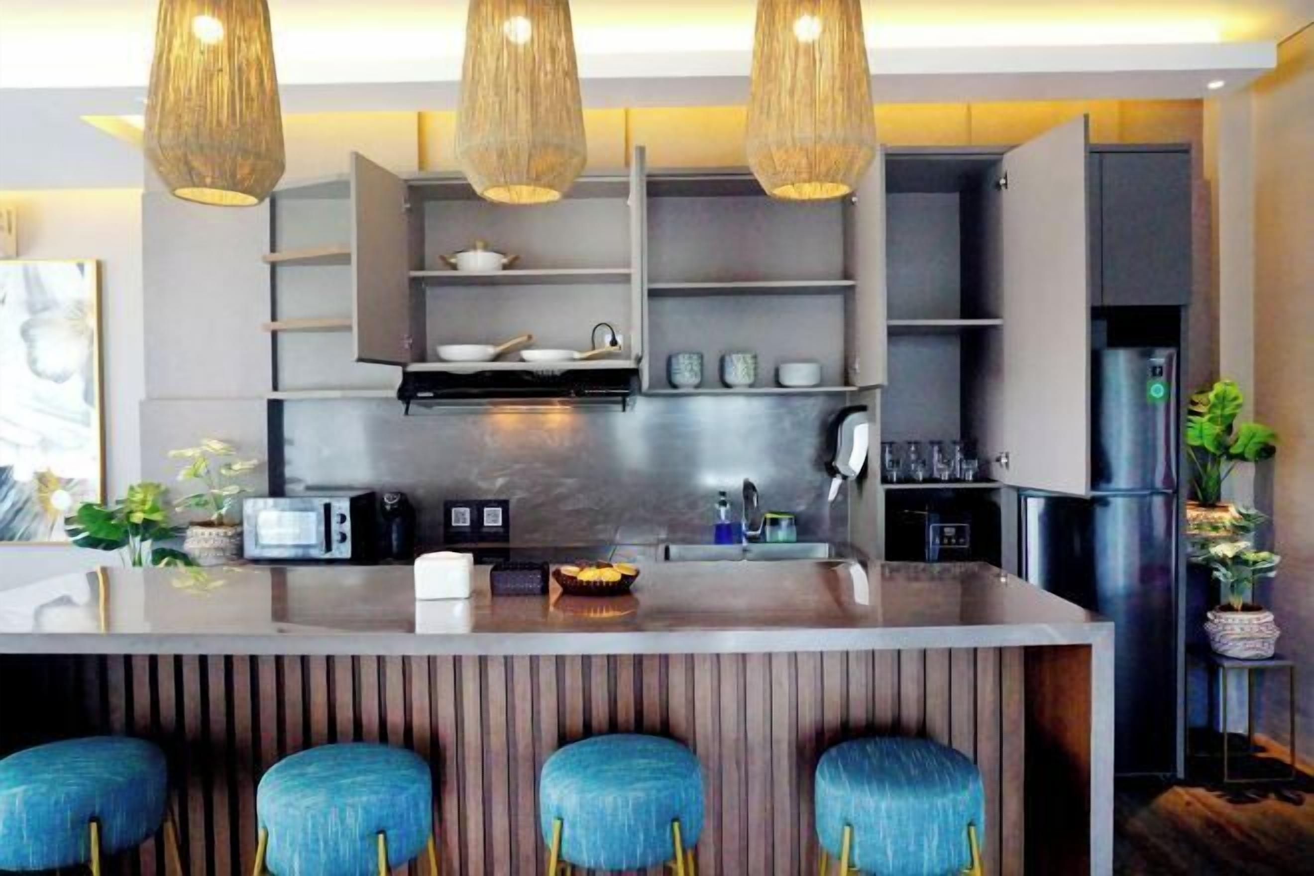 Cozinha moderna com ilha central, banquetas, iluminação pendente e armários embutidos.