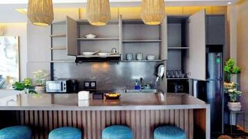 Cozinha moderna com ilha central, banquetas, iluminação pendente e armários embutidos.