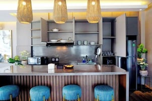 Cozinha moderna com ilha central, banquetas, iluminação pendente e armários embutidos.