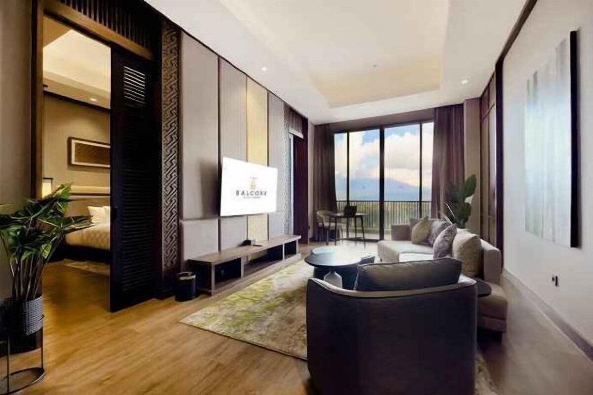 Quarto de hotel moderno com uma cama grande, TV, sofá e varanda com vista.