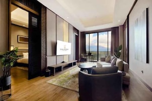 Quarto de hotel moderno com uma cama grande, TV, sofá e varanda com vista.
