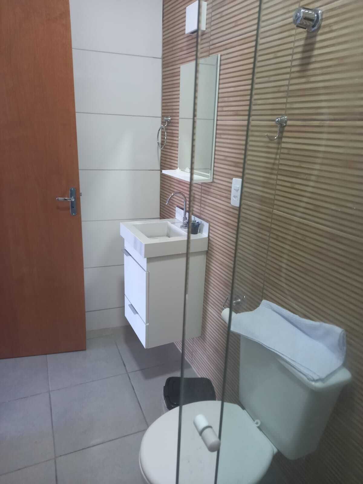 Um banheiro com vaso sanitário, pia e espelho.