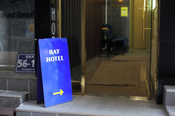 Placa azul com a inscrição 'BAY HOTEL' e uma seta apontando para a direita, indicando o caminho para o hotel.