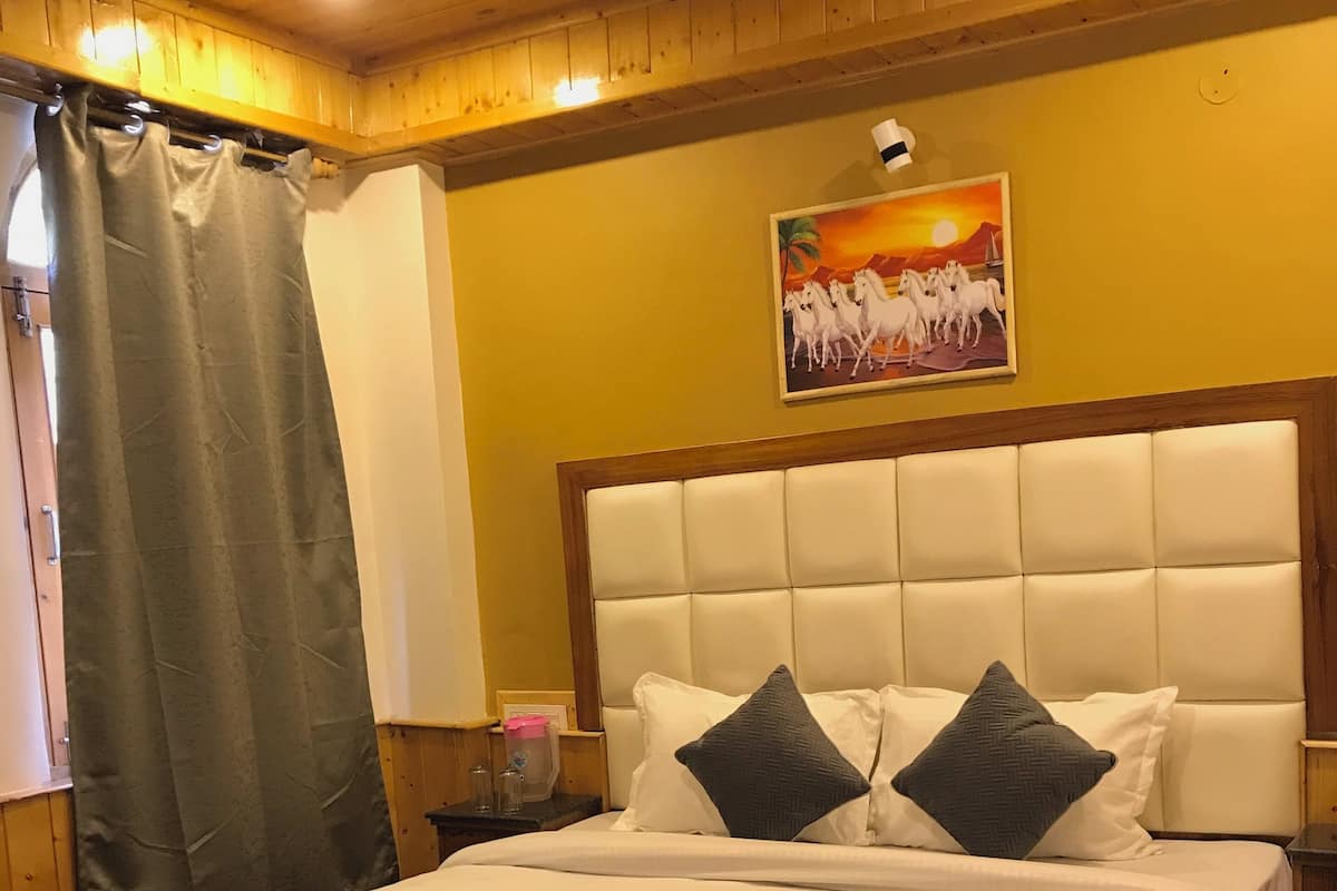 Uma cama com cabeceira, um quadro na parede e uma cortina.