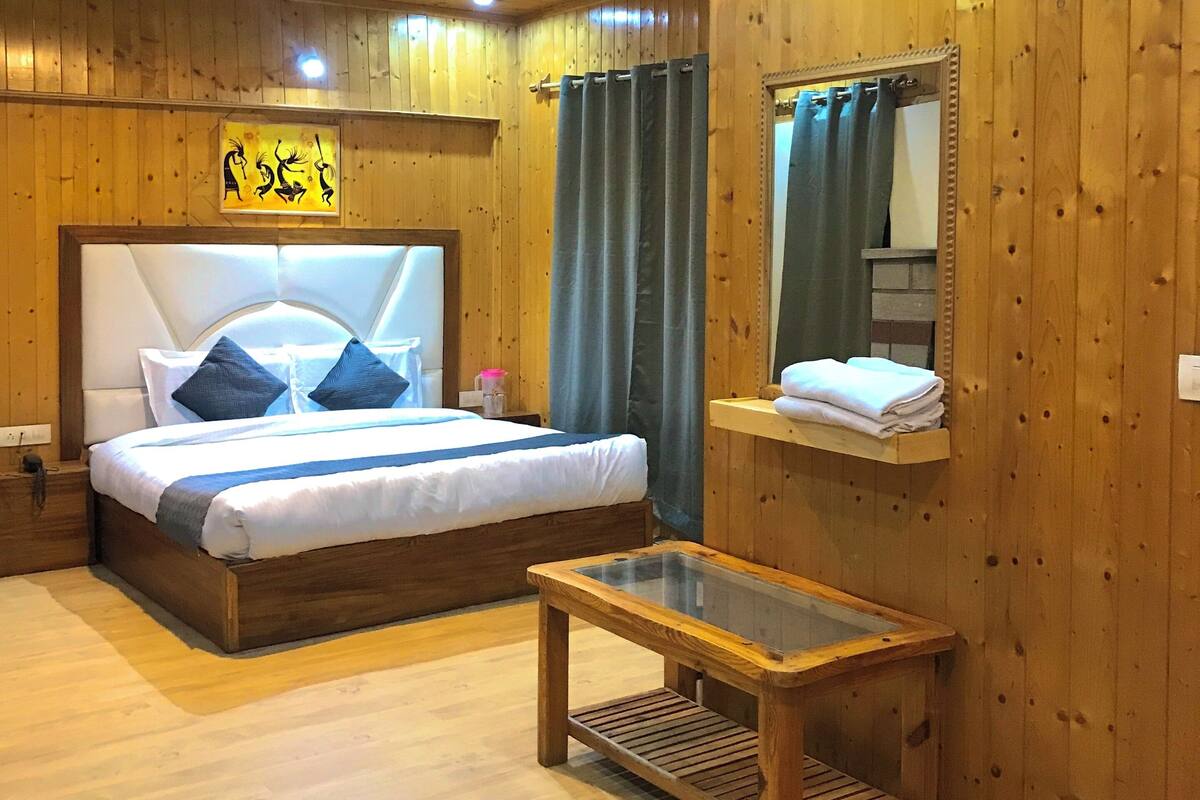 Um quarto com painéis de madeira, uma cama, uma mesinha e um espelho.