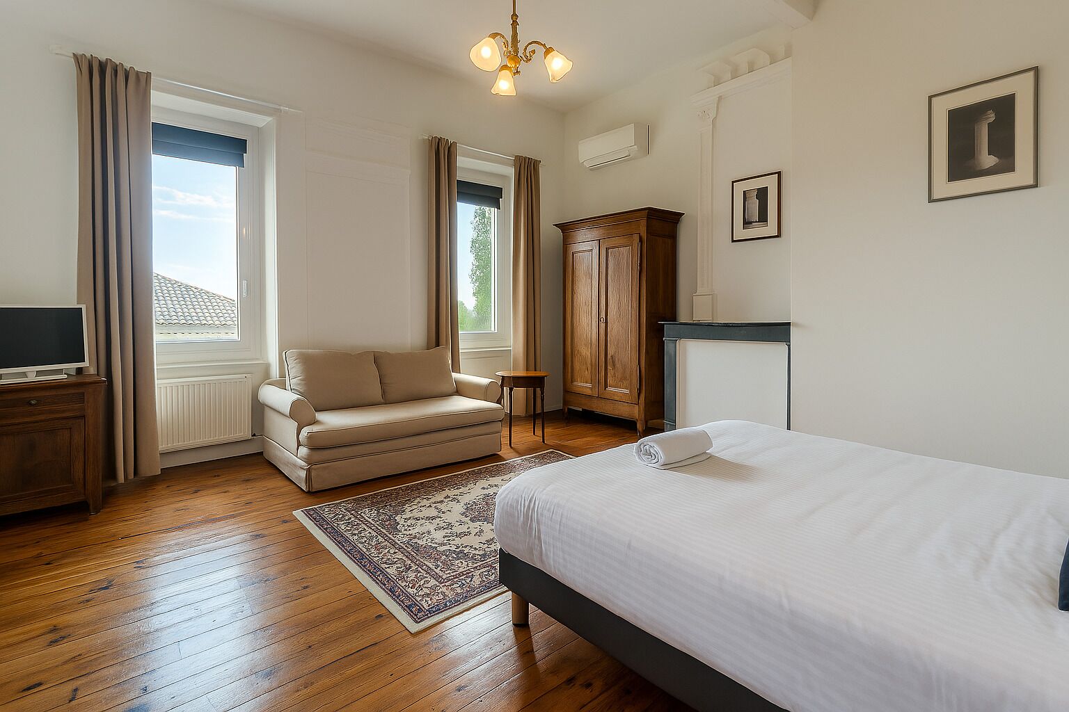 Quarto com cama, sofá, guarda-roupa de madeira, televisão e janela com cortinas.