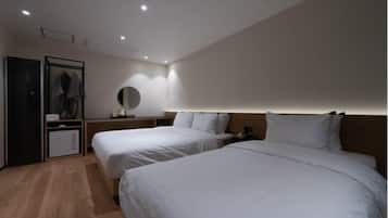 Quarto de hotel com duas camas, um guarda-roupa, um espelho e uma pequena mesa.