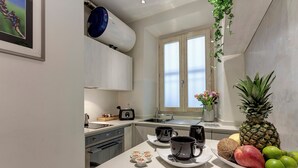 Uma cozinha com bancada branca, pia e janela com vista.
