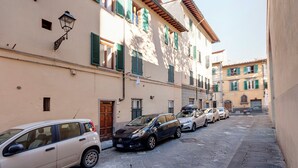 Rua estreita com carros estacionados e edifícios de arquitetura tradicional.