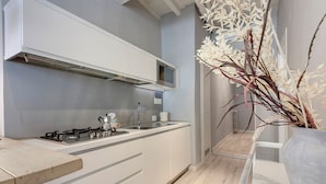 Uma cozinha moderna com armários brancos, fogão a gás e coifa de aço inoxidável.