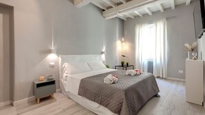 Quarto moderno com uma cama grande, mesas de cabeceira e televisão integrada.