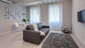 Uma sala de estar moderna com um sofá, uma mesa de centro e uma TV fixada em uma parede de tijolos.