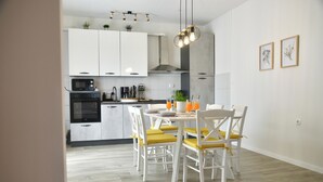 Uma cozinha moderna com armários brancos, uma mesa de jantar com cadeiras amarelas e um pendente.