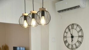 Uma sala de jantar com uma mesa branca posta para seis pessoas, cadeiras amarelas e um relógio na parede.