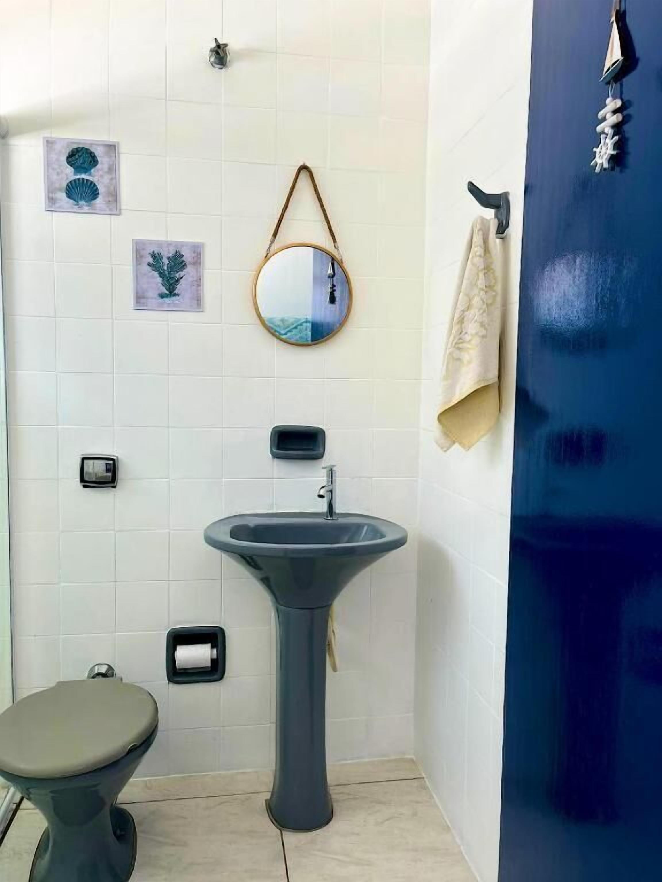 Um banheiro com pia de pedestal, vaso sanitário e porta azul.