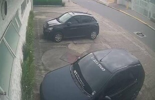 Um carro preto estacionado na rua, com um edifício de um lado.