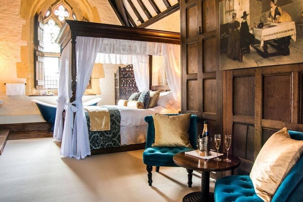Quarto com cama de dossel, área de estar com uma mesa e um mural na parede.