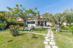 Uma casa com jardim, um caminho e um banco.
