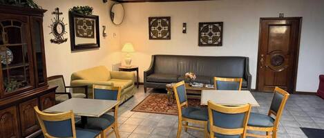 Quarto com mesa de jantar, cadeiras, sofá, armário e decorações nas paredes.