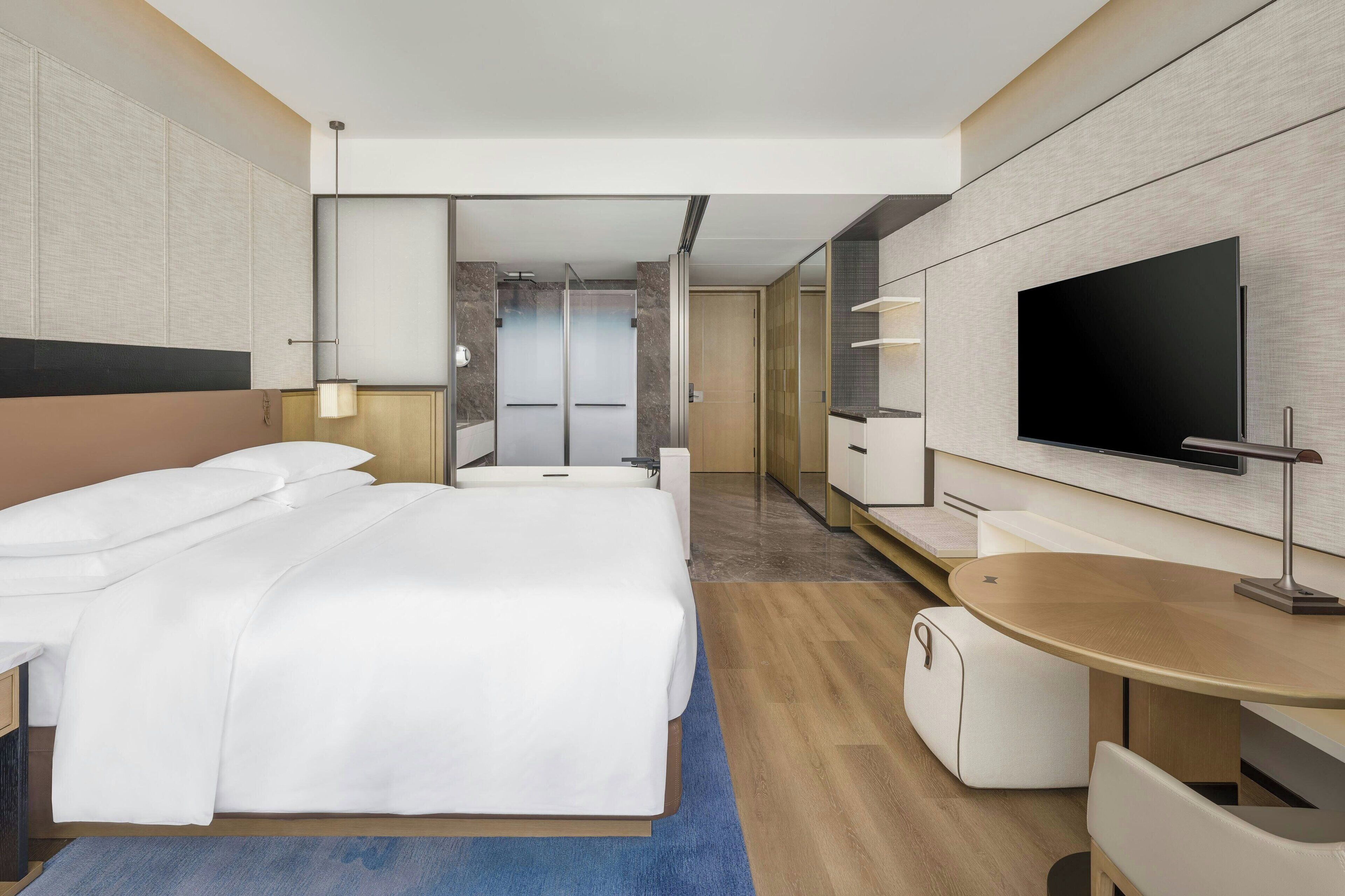 Quarto de hotel moderno com uma cama grande, uma escrivaninha com cadeira, TV de tela plana e um closet espaçoso.