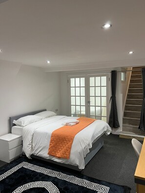 Quarto de hotel moderno com uma cama grande, uma escrivaninha e uma janela com cortinas.